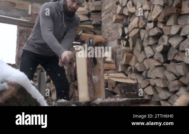 A man cuts wood logs with an ax. Felling of trees. A pile of sawn ...