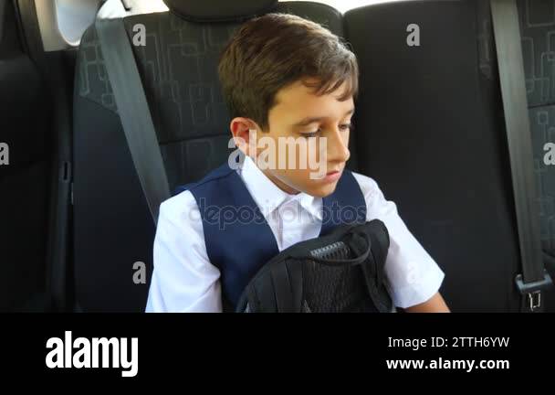 the sad boy is riding in the car in school uniform. 4k, slow-motion ...