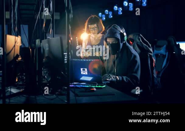 Two hackers working with a laptop. Cyber crime and hacking concept ...