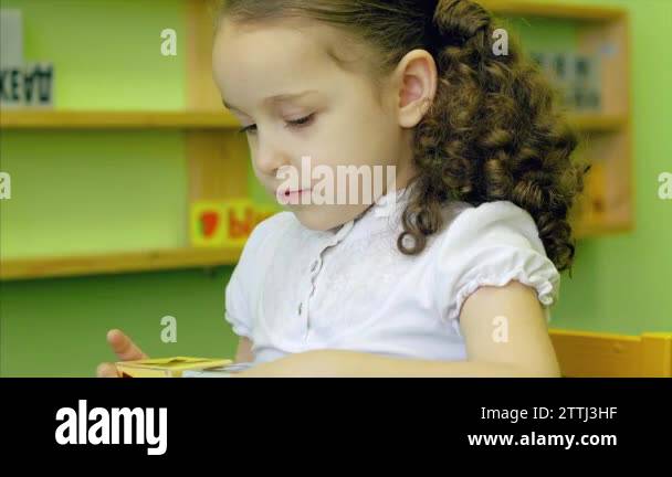 A girl studying the lessons, a pretty baby girl does her schoolwork ...