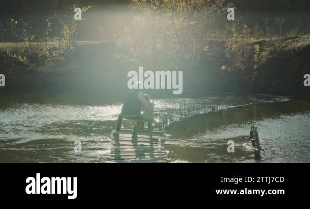 Wonderful view of a lake , dad and His son sitting on a chair in the ...