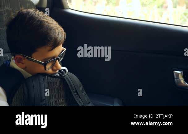 the sad boy is riding in the car in school uniform. 4k, slow-motion ...