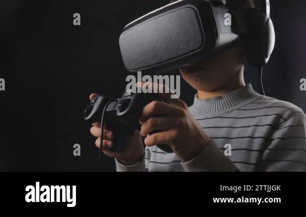 Boy uses VR-headset display with headphones and joystick for virtual ...