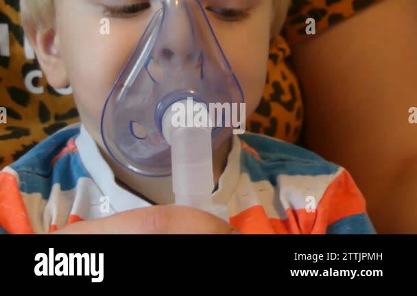 The boy breathes through an oxygen mask. The child takes inhalations ...