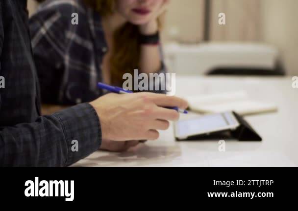 Tilt down of man and woman working on the tablet with diagrams Stock ...