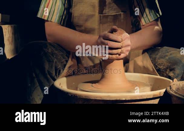 Potters hands reshape a tall tower of clay into a shallow pot Stock ...