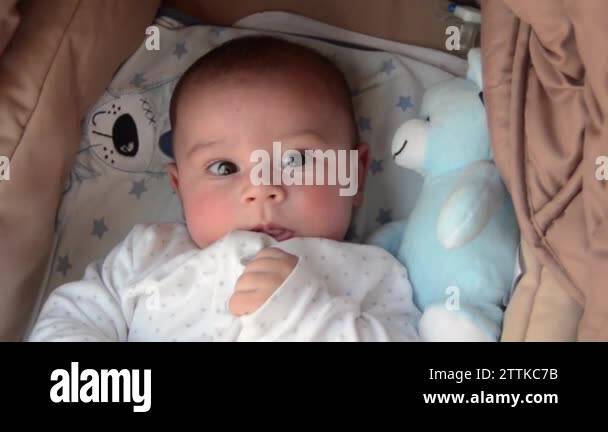 cute 3 months old baby boy making funny faces in baby carry cot Stock ...