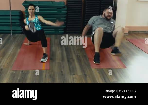 Thick obese man together with personal slim coach do physical jerks in ...