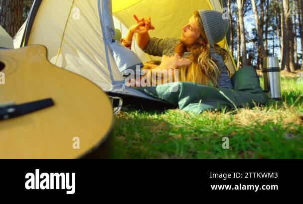 Romantic young couple holding hands in tent. Man kissing woman forehead ...