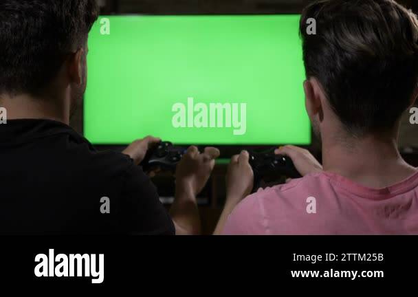 Competitive male friends enjoy playing video games with controllers ...