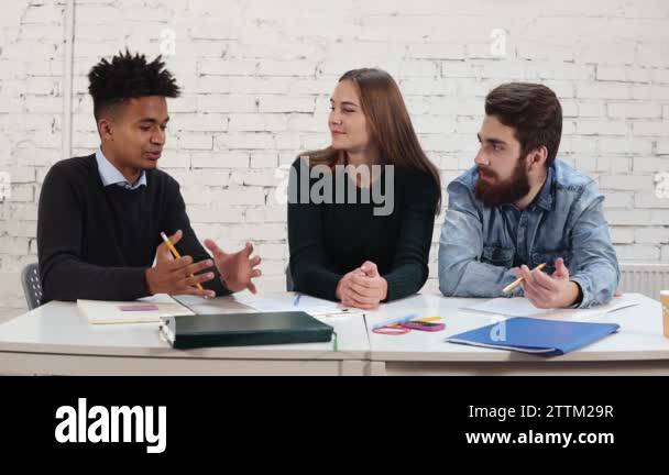Young african guy explaining something to his collegues. Multiethnic ...
