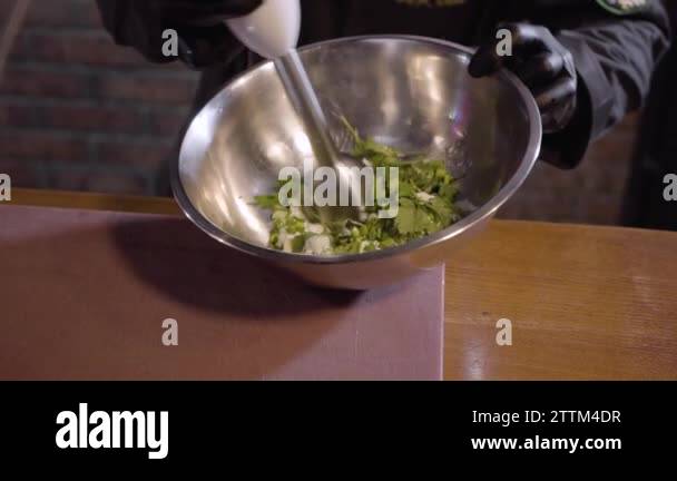 Hands of chef in black rubber cook gloves whipping cream with parsley ...