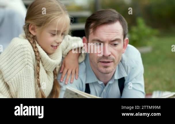 Family portrait. Young Girl Sitting Hugging Her Father and Reading a ...