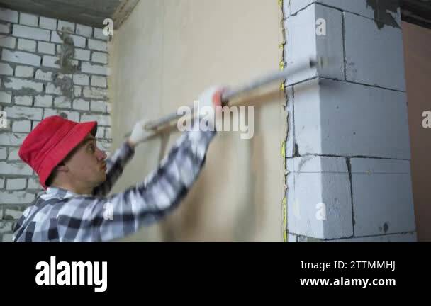 tilt down of builder smoothing plaster on interior wall with ...