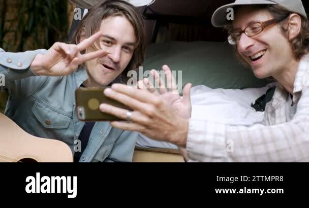 Two handsome men talking selfies with their smart phone camping ...