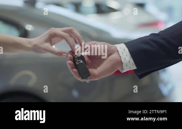 Male hand gives a car keys to famale hand in the car dealership close ...