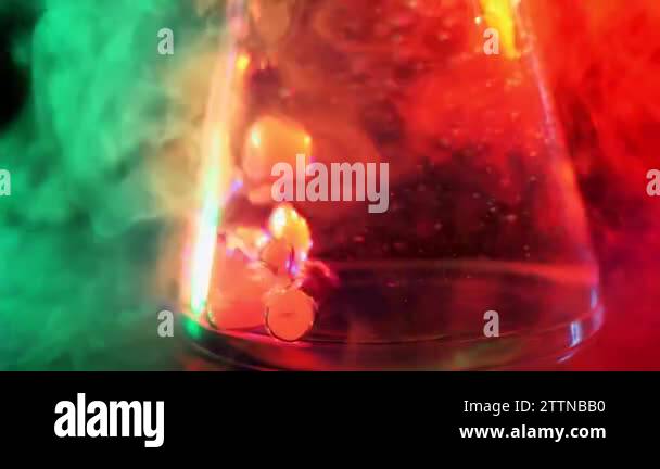 The liquid is boiling in flask in neon color light. Beautiful chemical ...