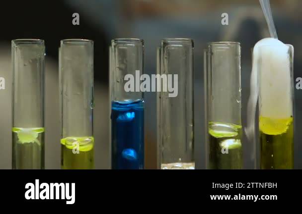 Lab worker adding liquid into test tubes, comparing boiling reaction ...