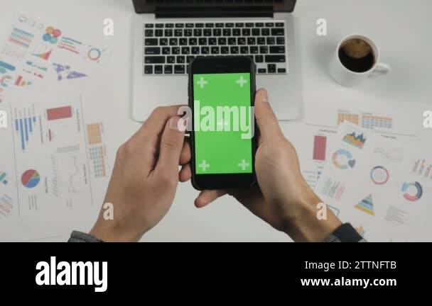 Businessman using smartphone with green screen at white office table ...