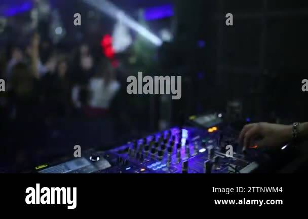 A professional DJ working in a club at a party winds a crowd of people ...