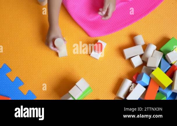 Little Asian cute girl playing cubes, sitting on a color floor. The ...