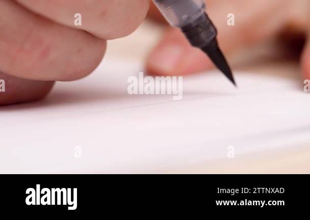 Calligraphist drawing letters on white blank. Close shot. Side view ...