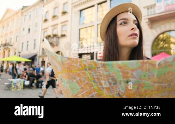 Beautiful young woman with tourist map looking aroung in the city ...