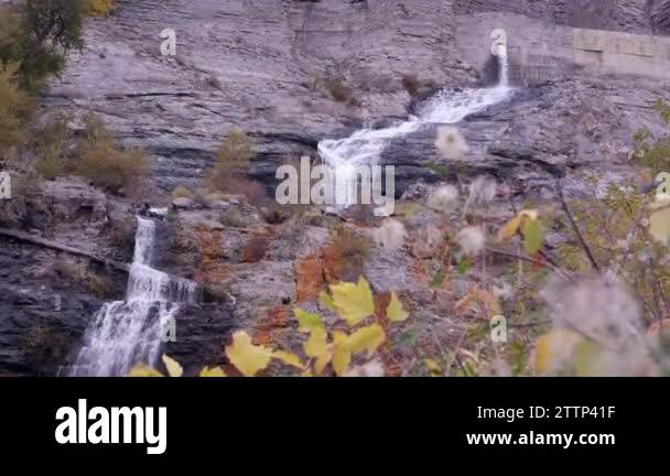 Trucking forward shot of a waterfall cascading over the rock cliff ...