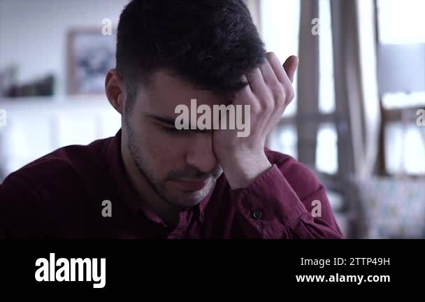 Close up view of sleepy young man working late at night, rubbing his ...