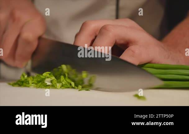 Cut the green onions with a knife on the board. Cutting green without ...