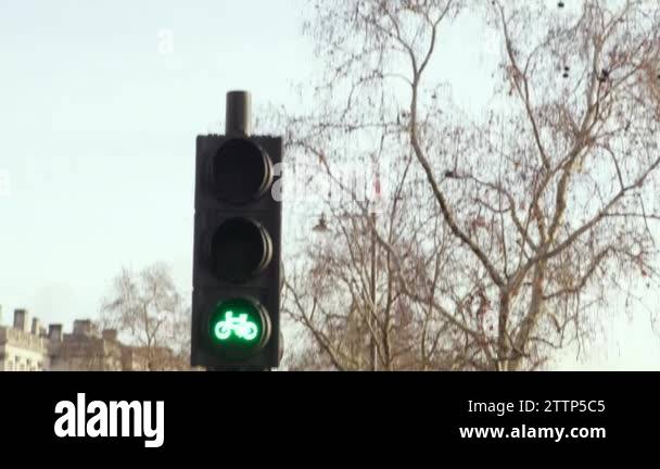 Cyclists ride in a busy cycle lane in London with cycle traffic lights ...