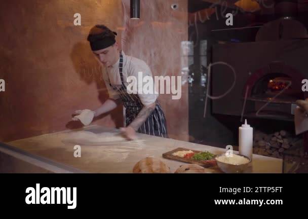 Skillful pizza maker is cooking dough at modern restaurant kitchen ...