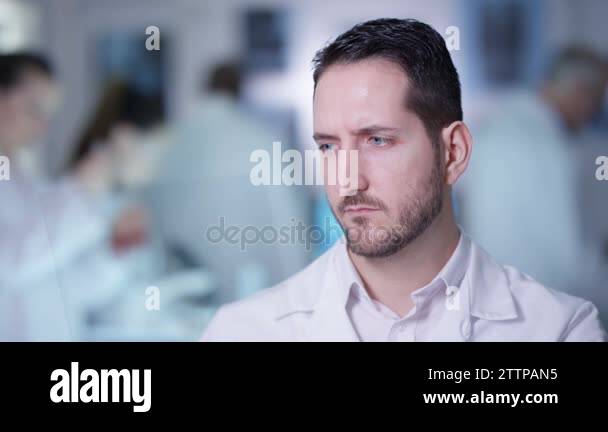 male scientist in white coat holding piece of clear material and using ...