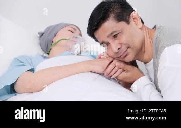 Asian senior man talking to his sick wife in bed in hospital, very much ...