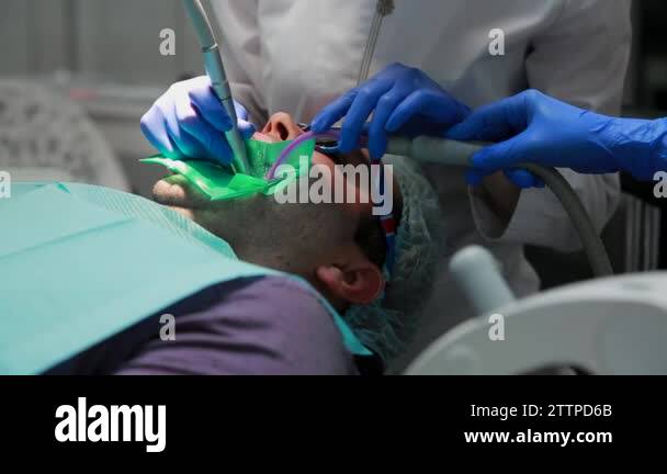 The dentist and nurse repairing a tooth of a patient man. The use of ...
