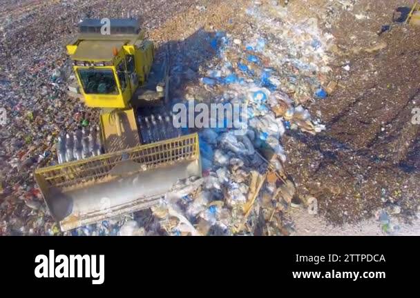 A landfill compactor bulldozer tractor levels out a garbage pile Stock ...