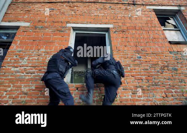 Two soldiers with modern ammunition enter a red brick building through ...