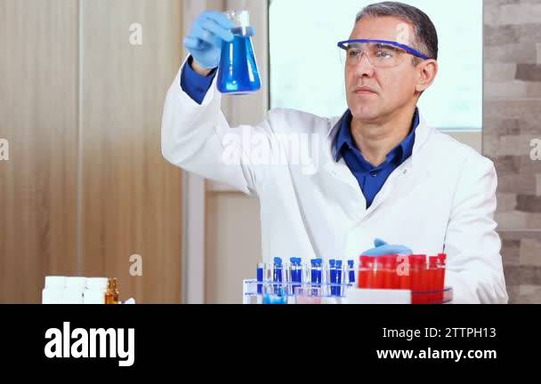 Middle Aged Scientist Examining a Beaker of Blue Fluid. Scientist ...