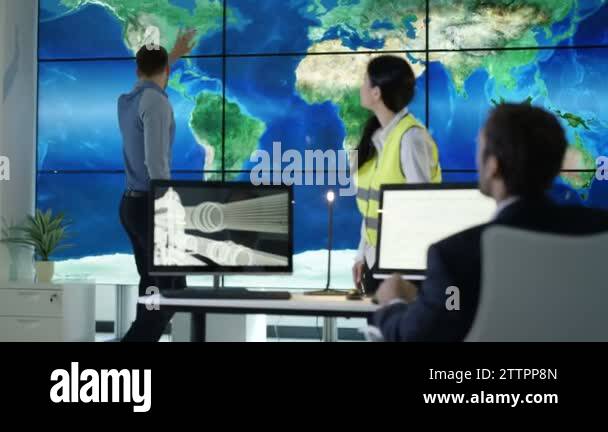4K Engineering team in discussion looking at large world map graphic on ...