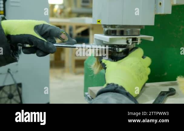 Operator of a modern CNC woodworking machine makes adjustments before ...