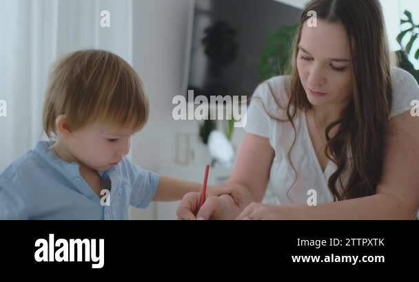 Mom helps two sons of 2 and 4 years old to do preschool homework to ...