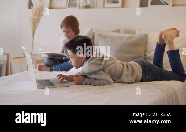 Boys in parents bed at morning with laptop and tablet. Brothers play ...