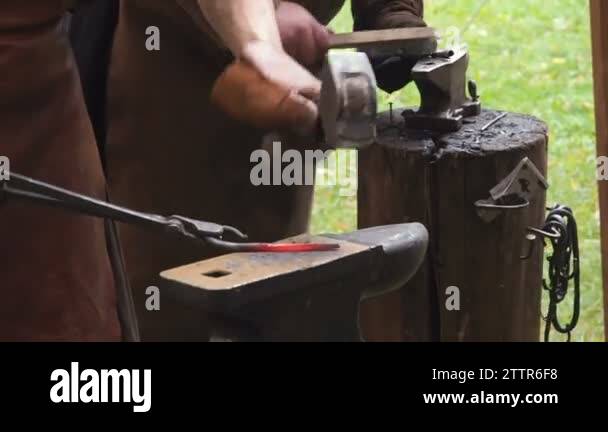 Two blacksmiths in the production process of metal products handmade on ...