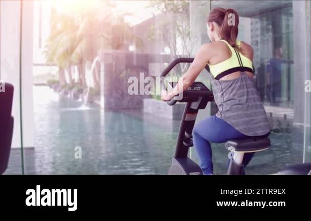 Back view of attractive woman at the gym riding on the spinning bike ...