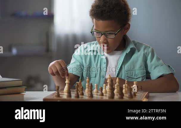 African American boy logically thinking out strategy of playing chess ...