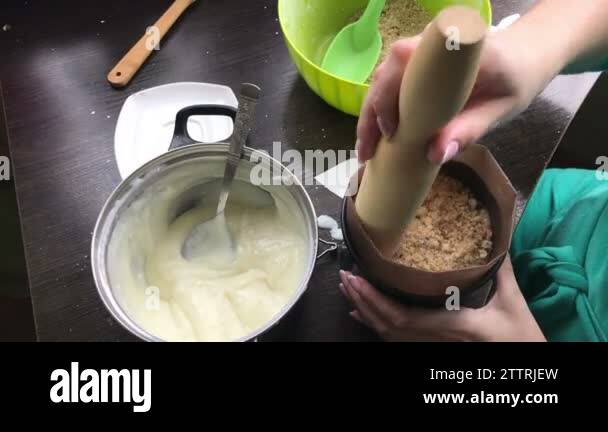 Woman adds sponge cake to cake mold. Cooking a cake of biscuit crumbs ...