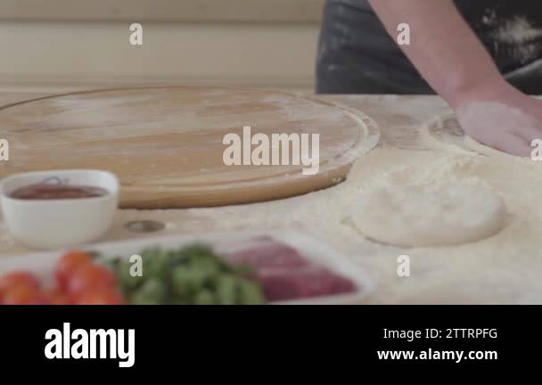 Close up hands of young pizza maker in cook uniform forming a pizza ...