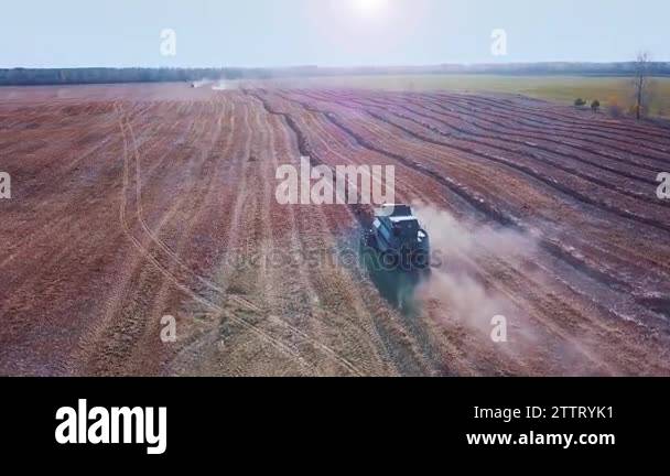 aerial footage of a modern tractor plowing dry field, preparing land ...