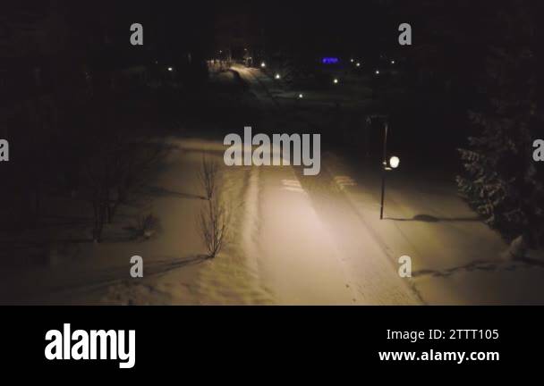 Snow-covered paths illuminated by street lights on winter night. Clip ...