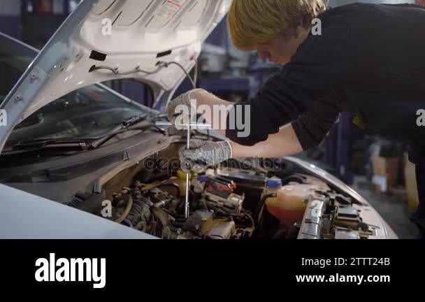 a young man is spinning with the help of a tool the engine from an auto ...